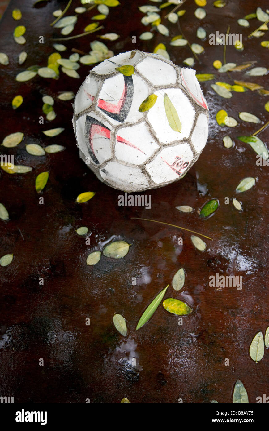 a well worn used deflated football in the rain on a table surrounded by ...