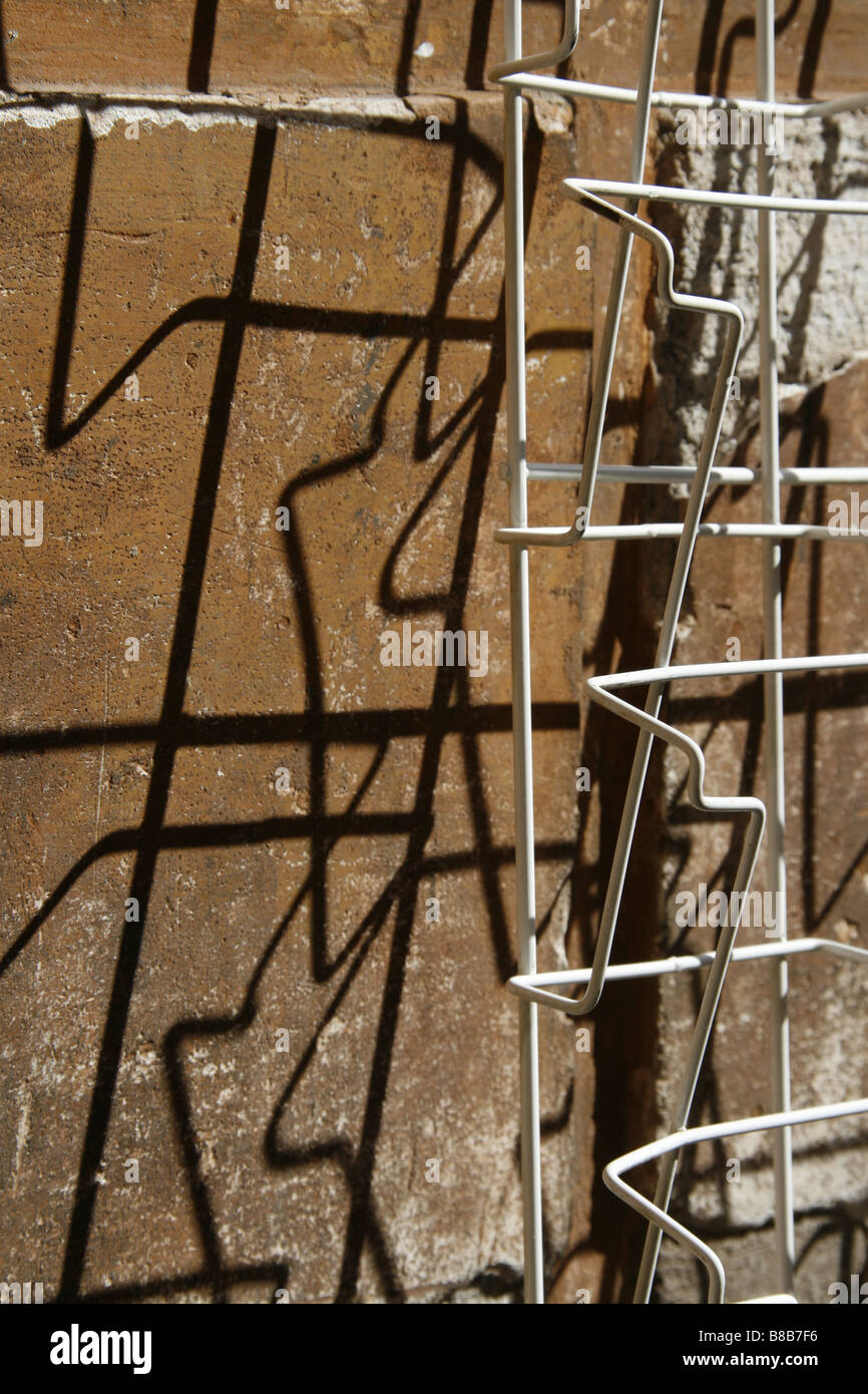 empty newspaper stand rack shadow on wall in sun Stock Photo - Alamy