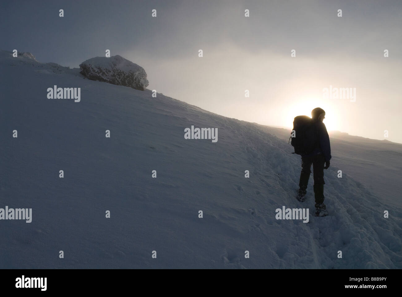Female hill walker ascending the munro of An Caisteal in winter ...