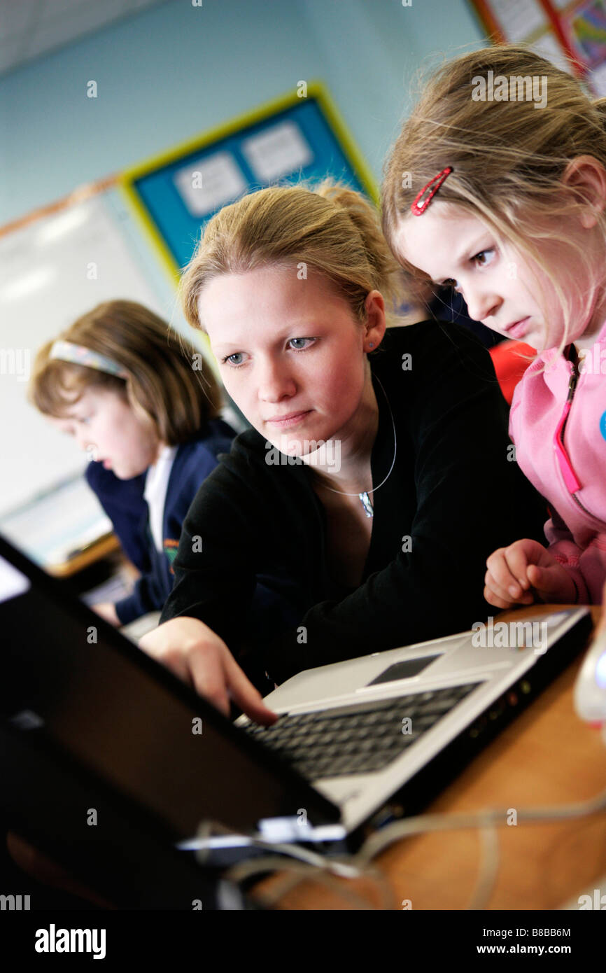 teacher working with primary school pupils on laptop computer Stock ...