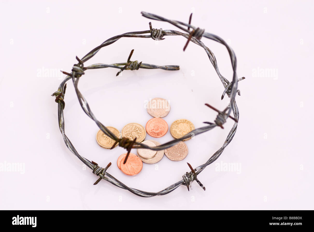 Barbed wire around money coins Stock Photo - Alamy