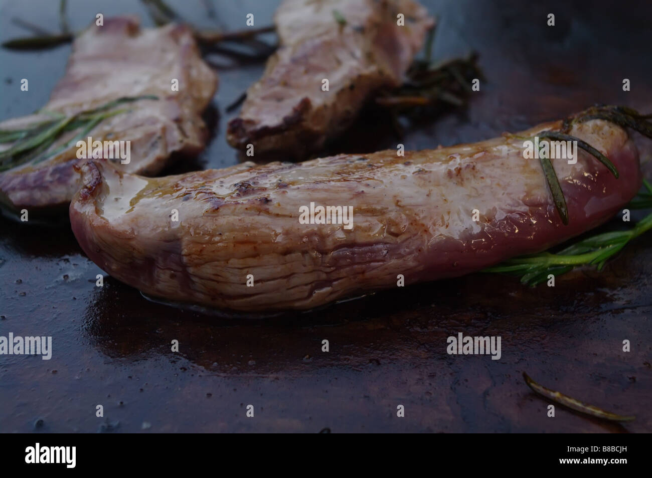deer meat on bbq flagstone with rosemary Stock Photo - Alamy