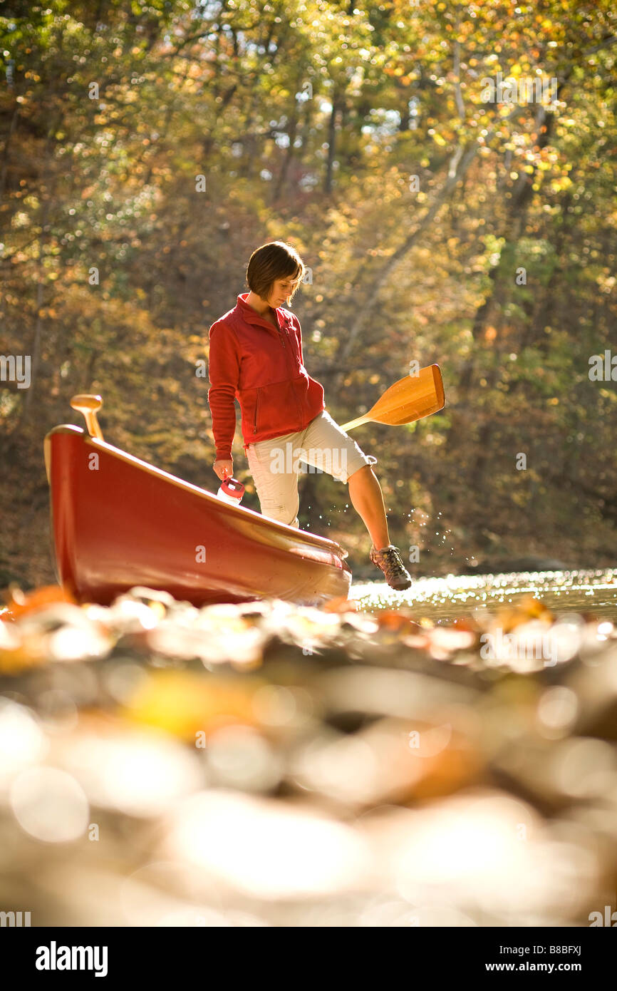 Woman stepping out of canoe in the river Stock Photo - Alamy