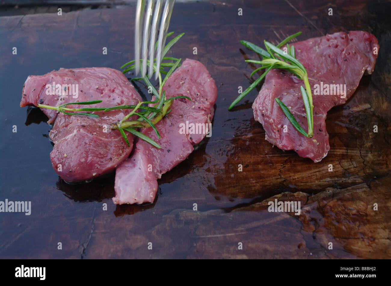 deer meat on bbq flagstone with rosemary Stock Photo - Alamy