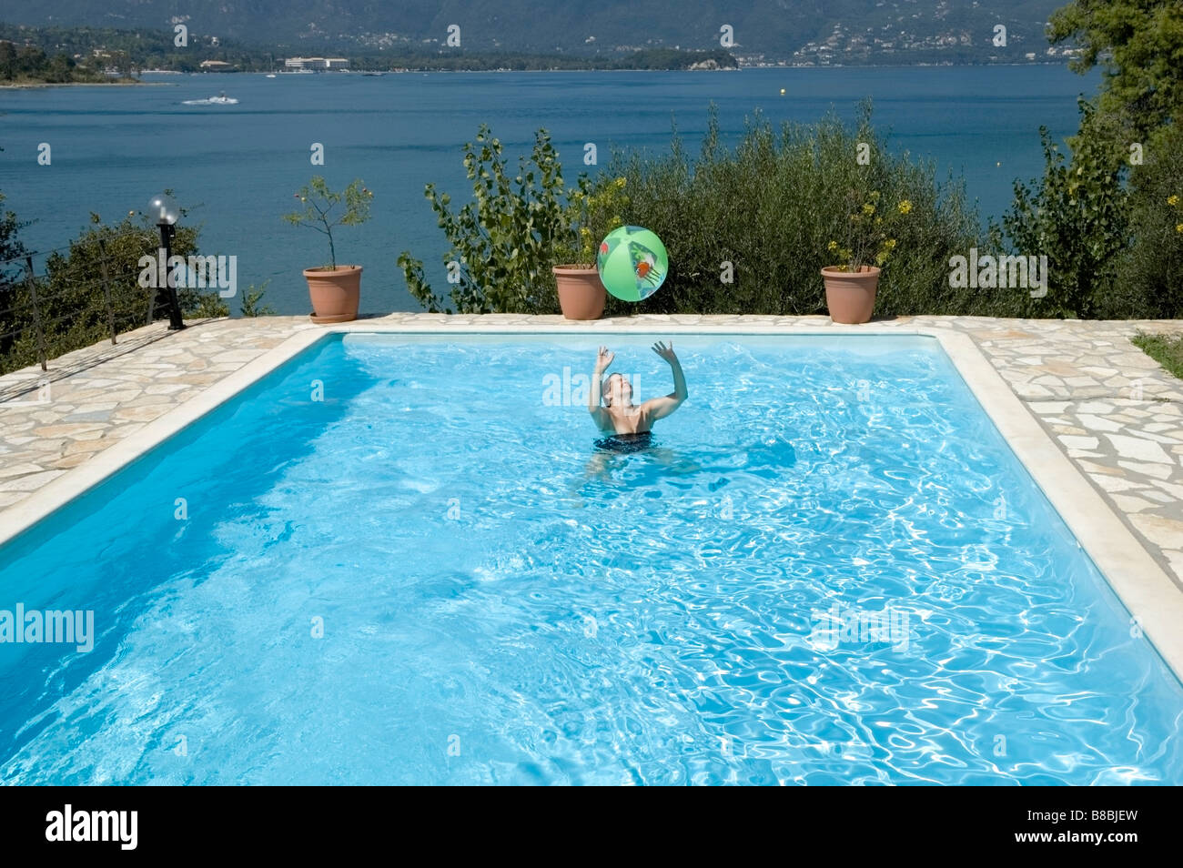 One women standing in swimming pool playing with green beach ball, Eva ...