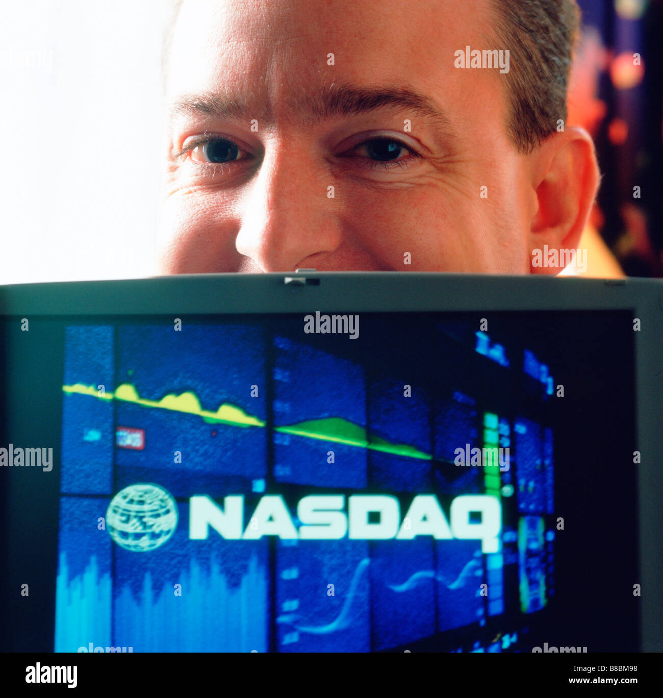 Man Looking Over Computer Screen that says NASDAQ Stock Photo - Alamy