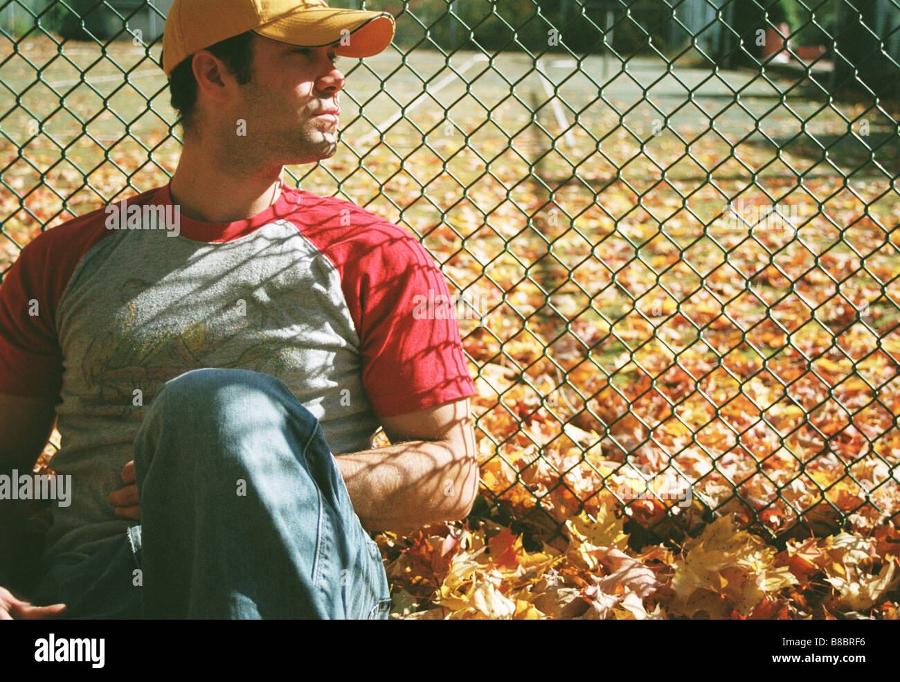Young Man sitting by Fence Autumn Stock Photo - Alamy
