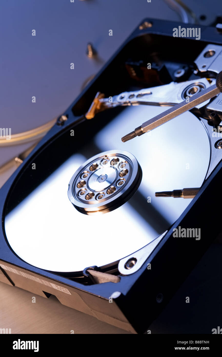 a opened hard disk drive with a hex screwdriver reflected on the disk ...