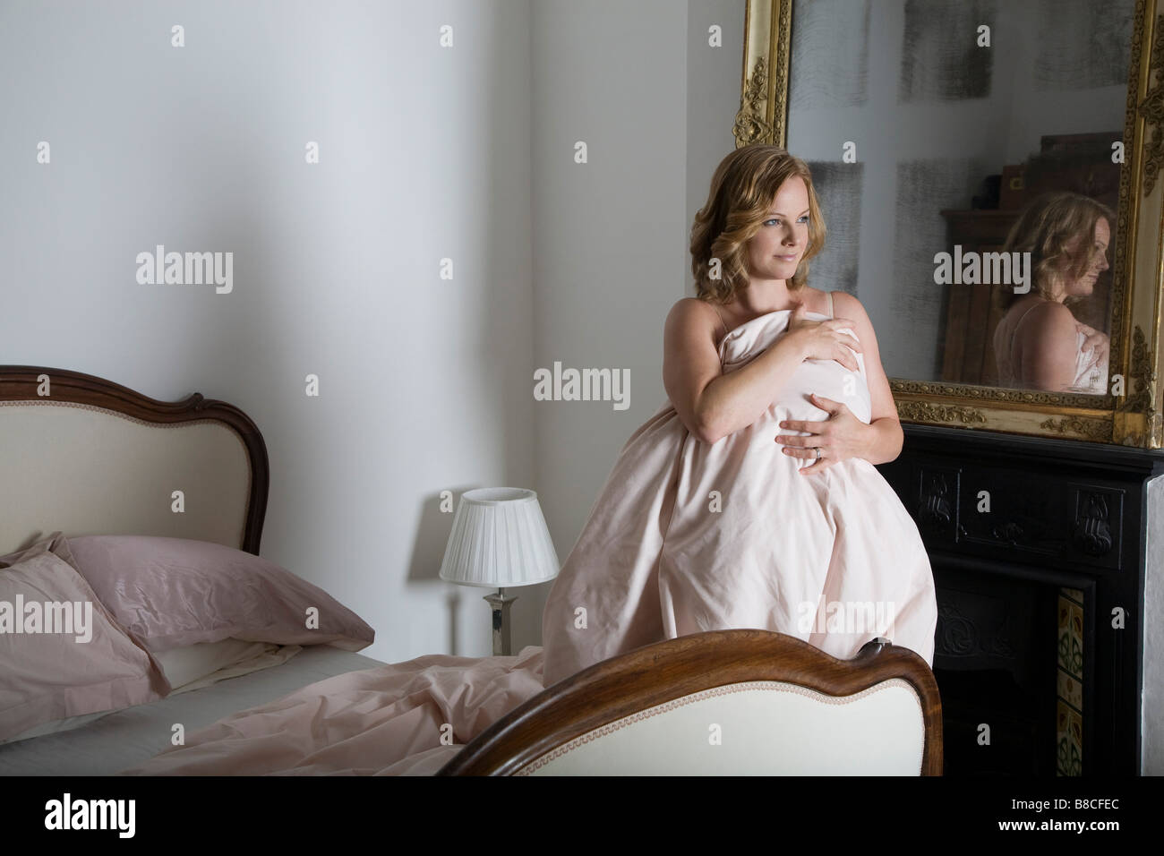 Mid adult woman getting up from bed Stock Photo - Alamy