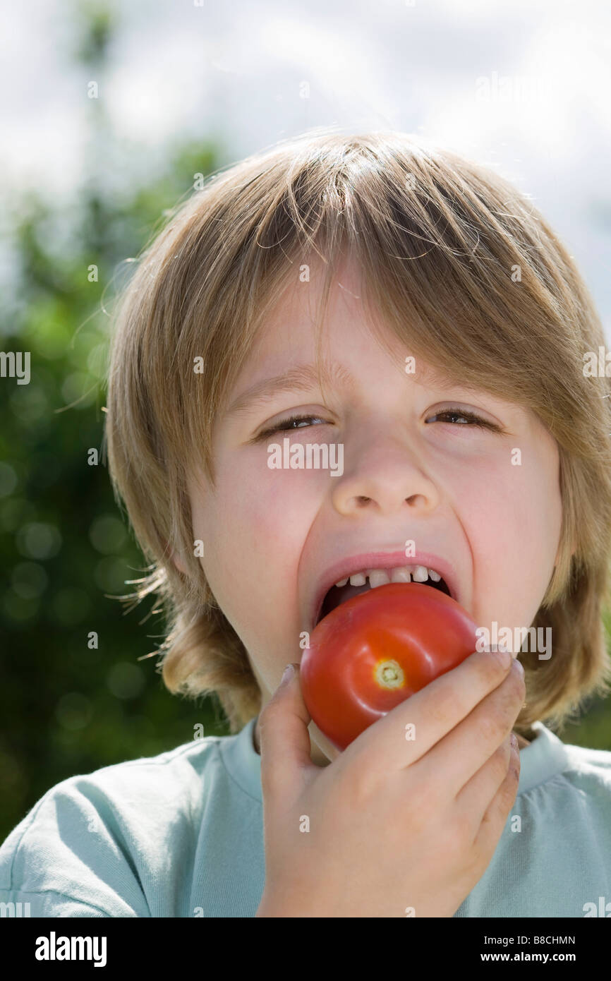 Boy eating tomato in garden, portrait Stock Photo - Alamy