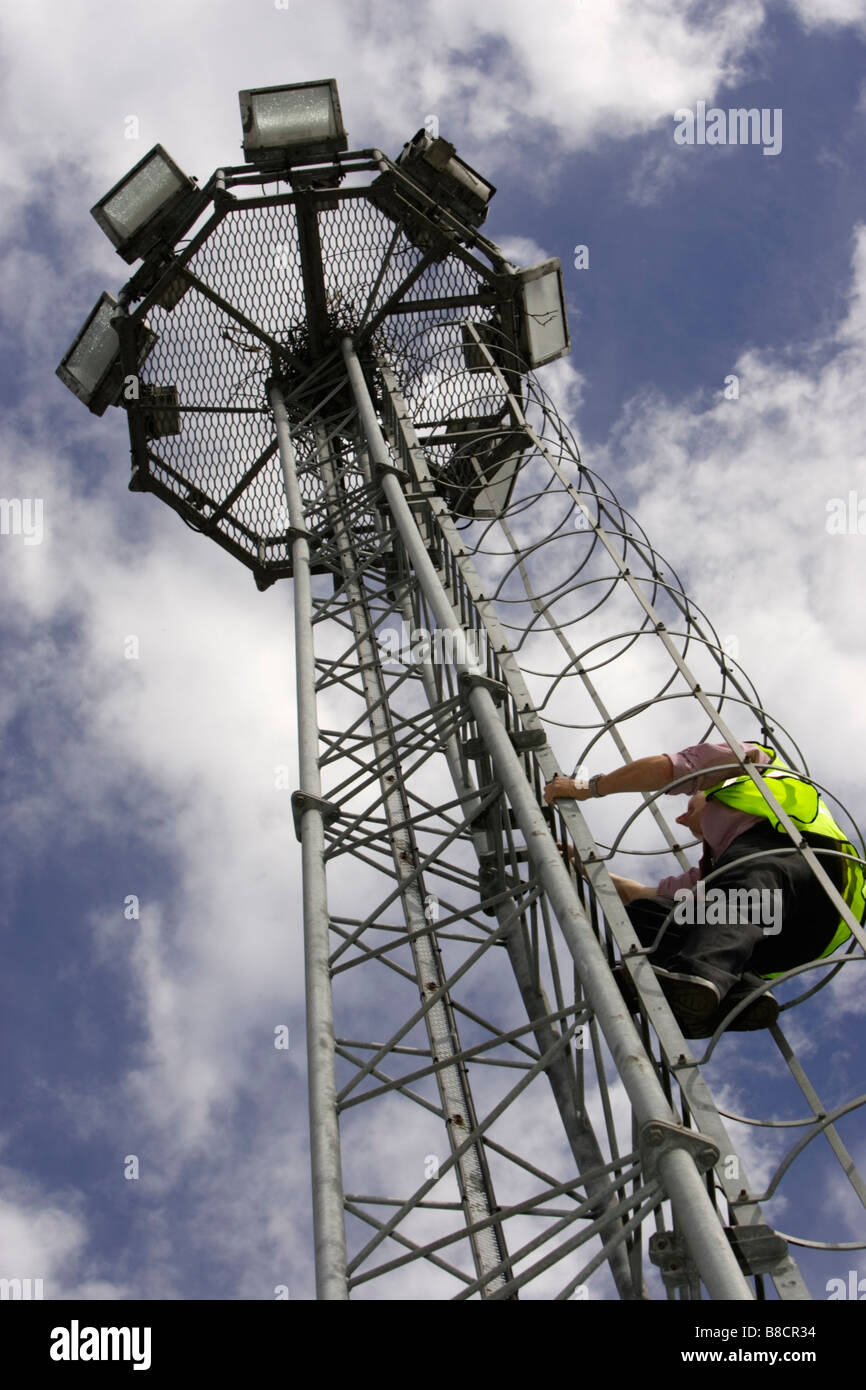 Man climbing outdoor lighting tower Stock Photo - Alamy
