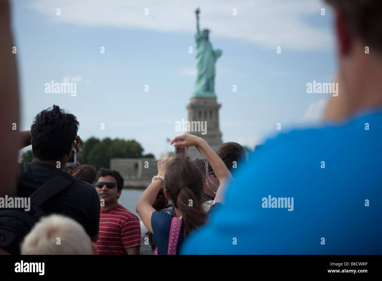 crowd of tourists near the statue of liberty visiting and takeing ...