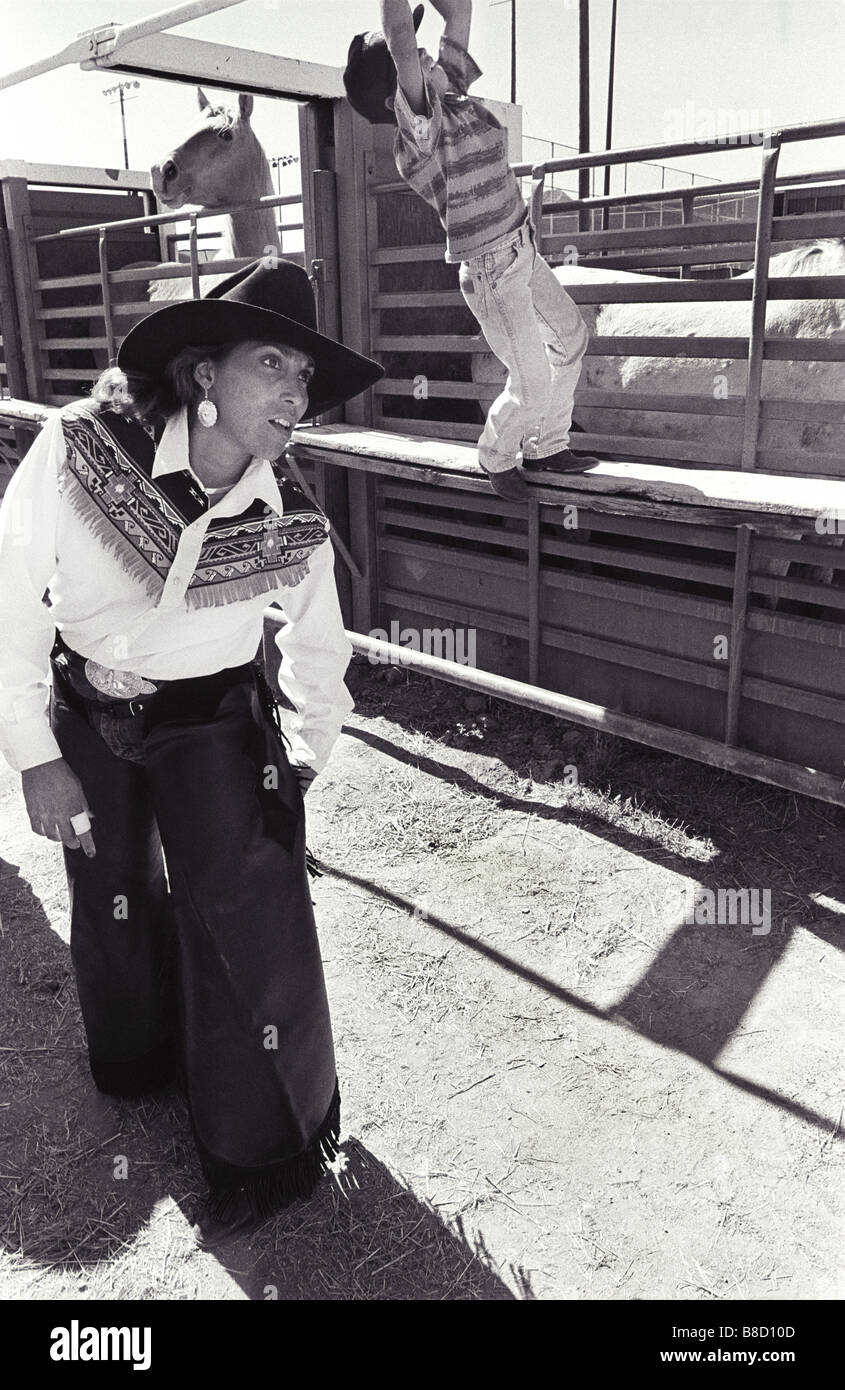 Mother cowgirl with son playing in background at a rodeo in Durango ...