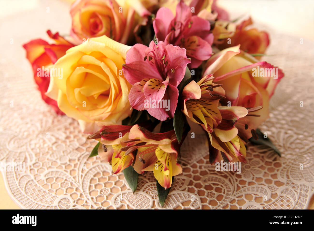 roses and alstroemeria (Peruvian lilies) in warm colors on lace Stock ...