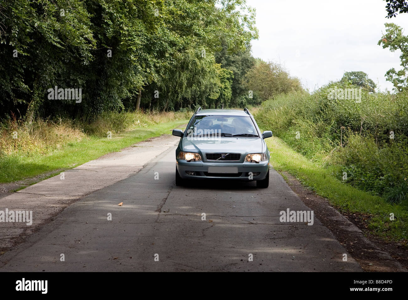 A light blue estate car travels along a quiet English country lane ...
