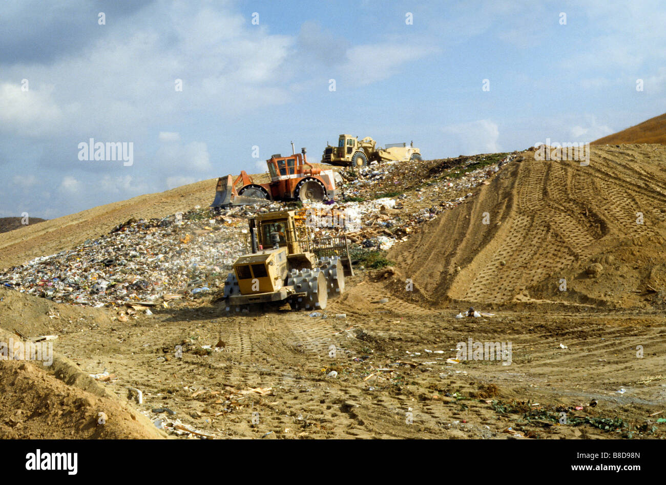Earthmovers cover waste at landfill site California Stock Photo - Alamy