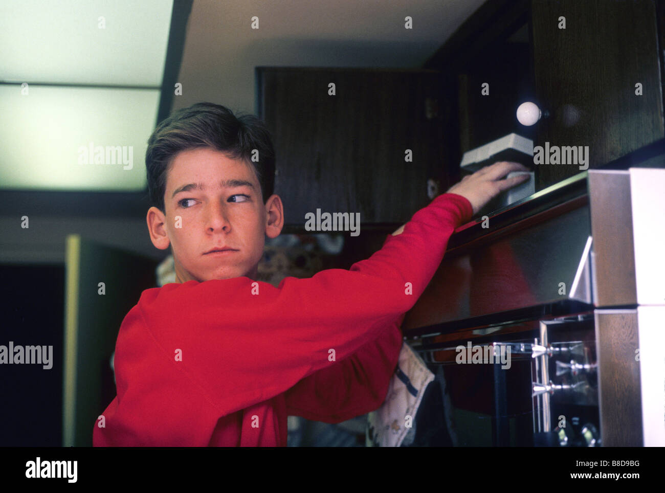 Teen boy sneaks into secret box crime wrong take sin Stock Photo - Alamy