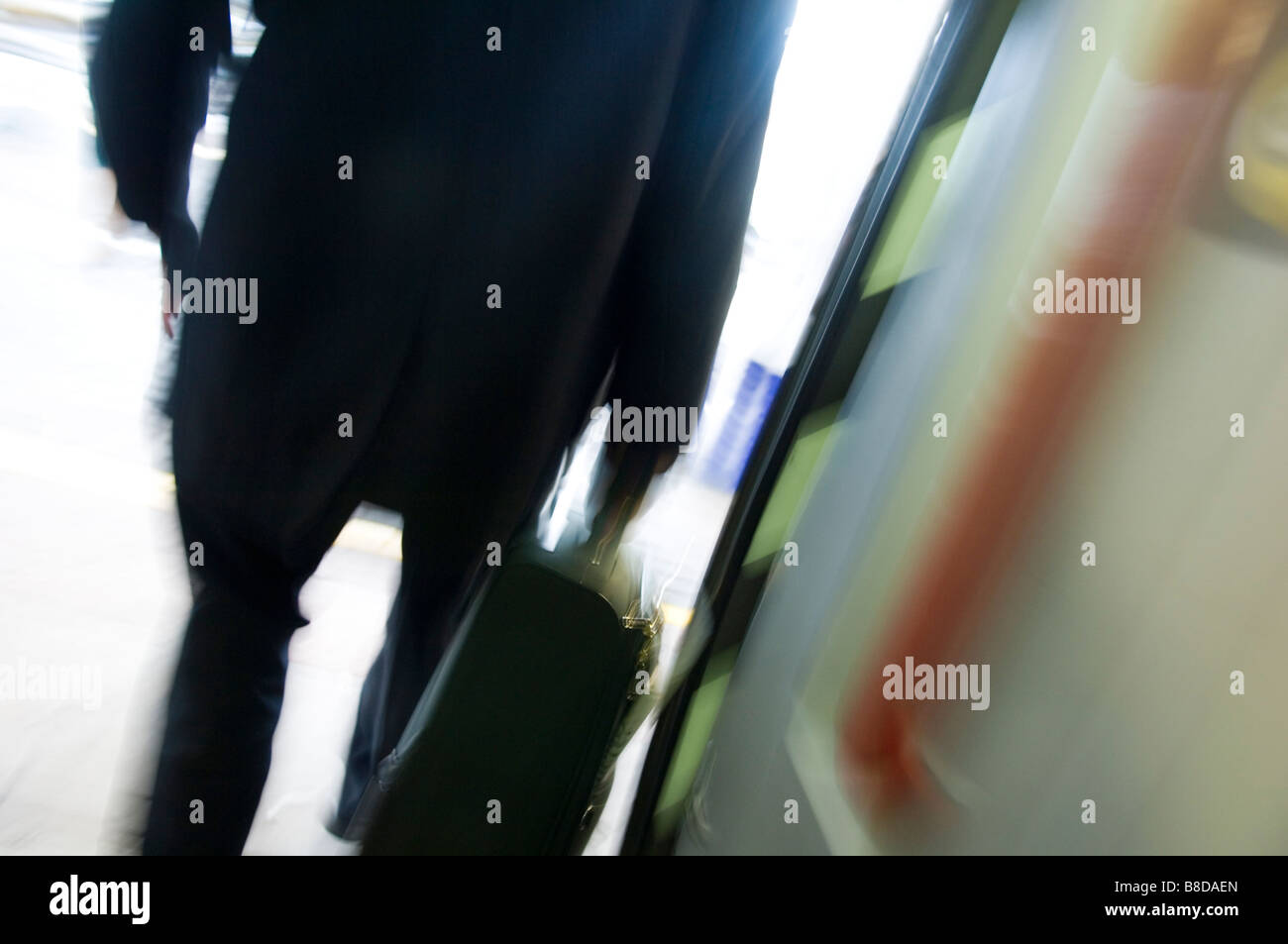 A male business commuter with a suitcase alights from a train in ...