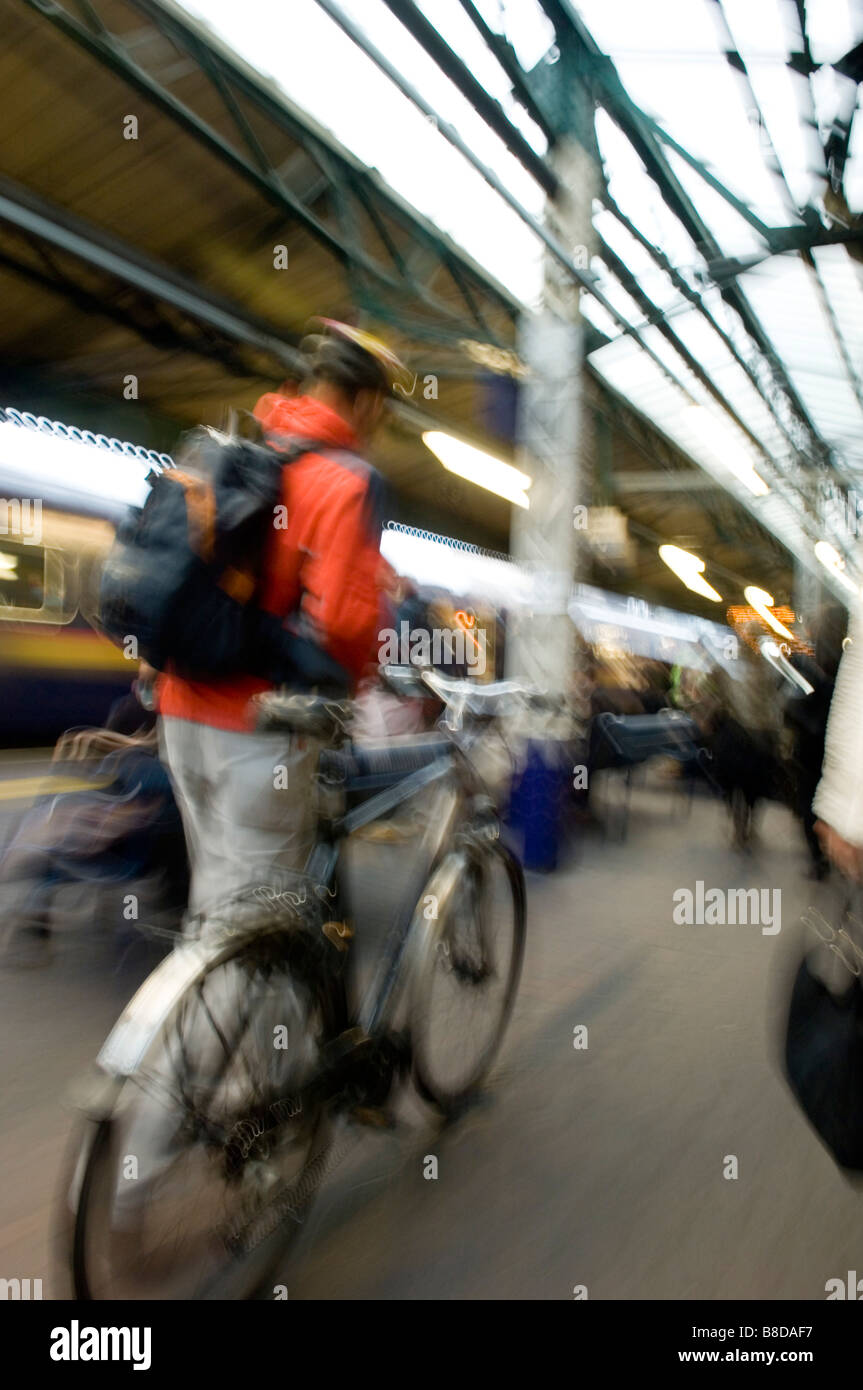 A male commuter pushing a bicycle and wearing suitable safety gear ...