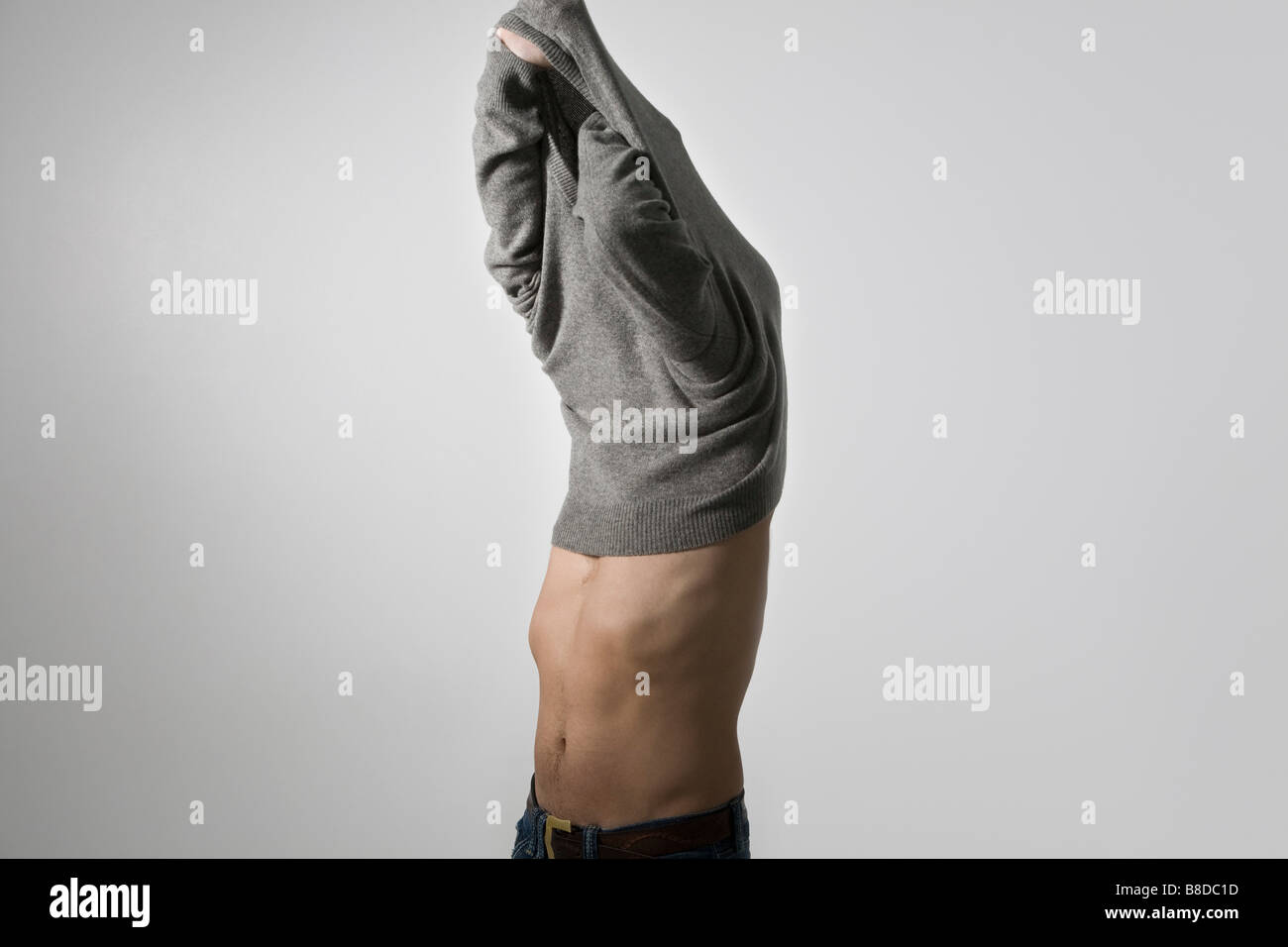 Mid-adult man pulling sweater over head Stock Photo - Alamy