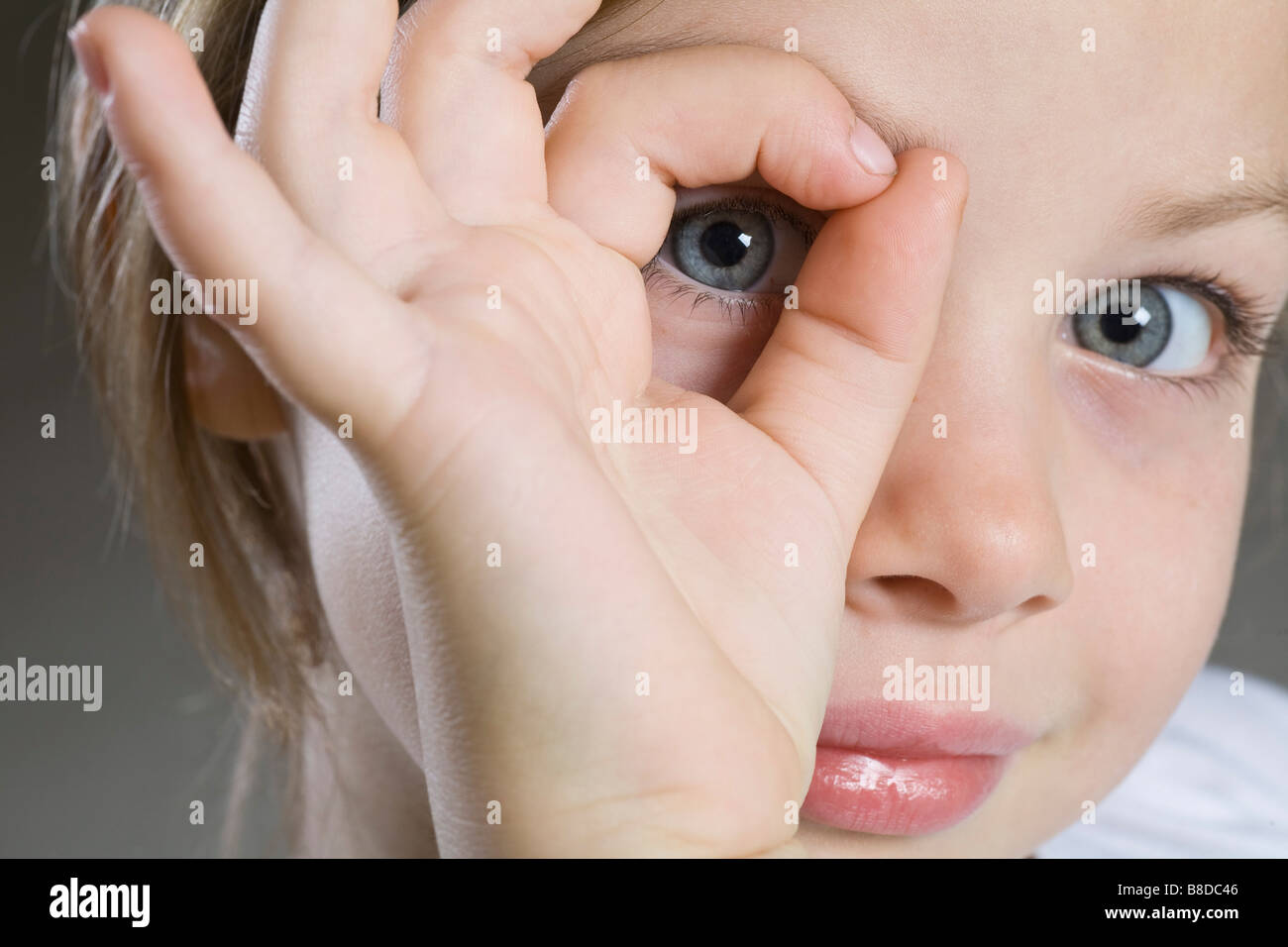 Studio portrait of girl peeking through hand, close-up Stock Photo - Alamy