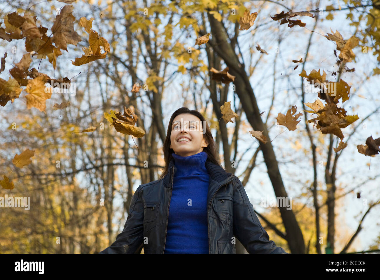 Woman under falling leaves in park Stock Photo - Alamy