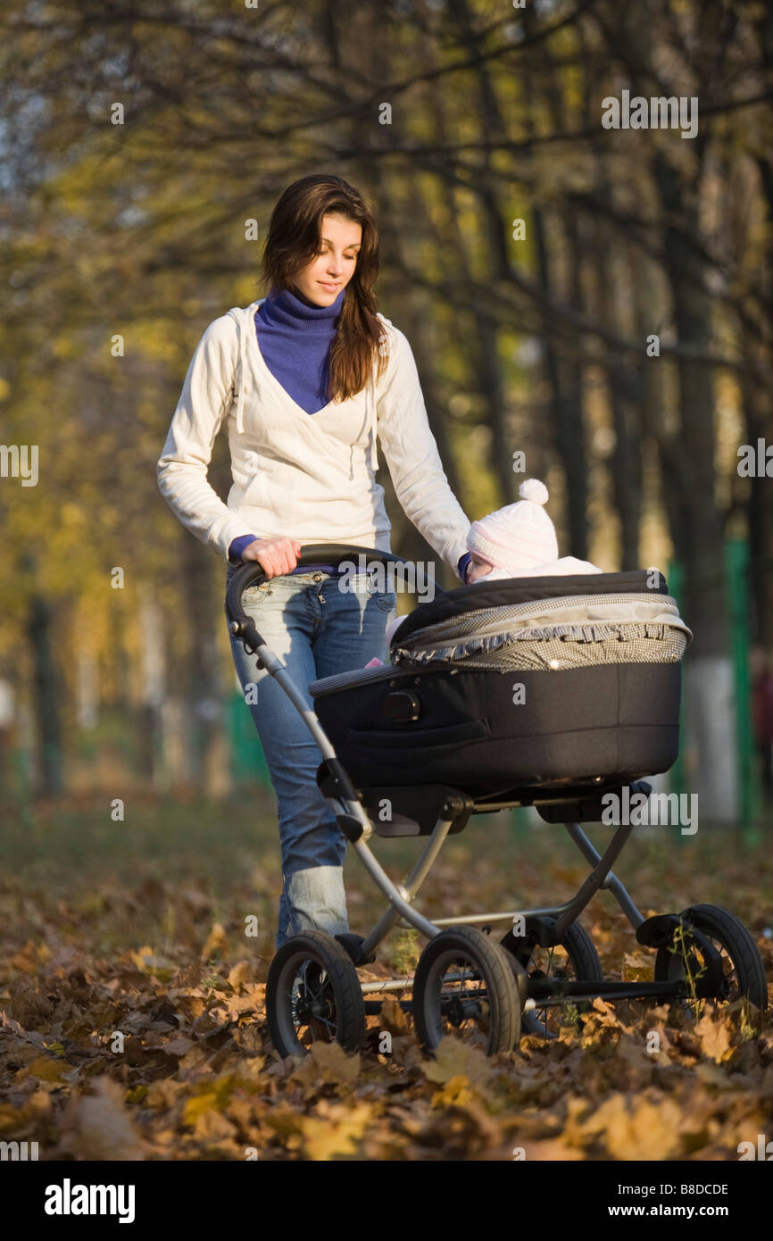Woman walking with baby in pram in park Stock Photo - Alamy