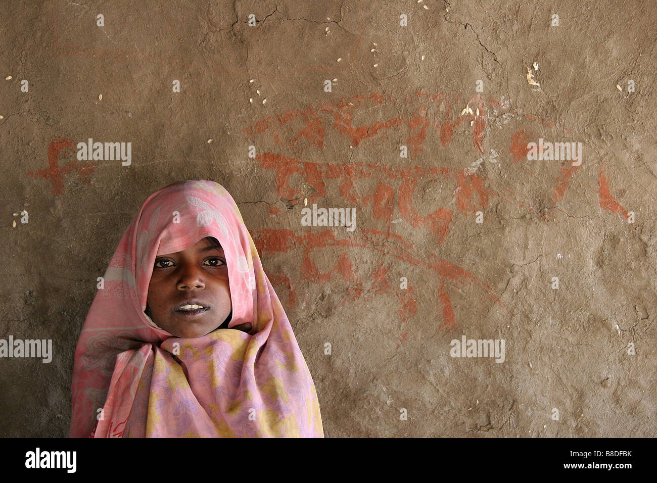 Indian girl poses for picture against mud wall Stock Photo - Alamy