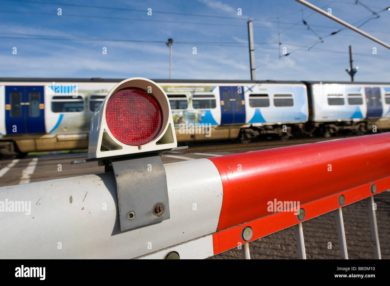 Passenger train speeding between barriers on a level crossing on the ...