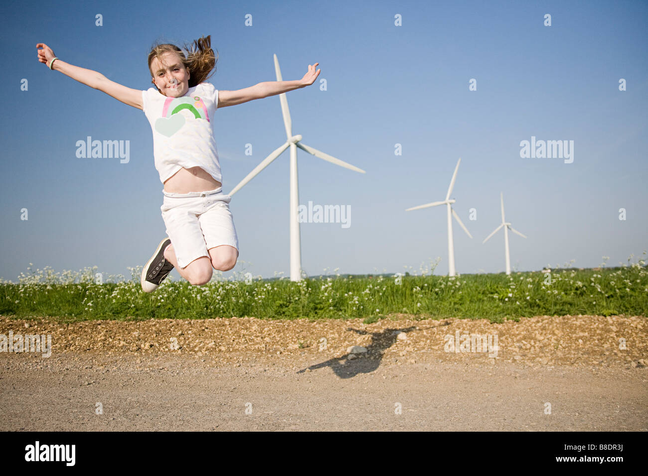 Girl jumping near wind farm Stock Photo - Alamy