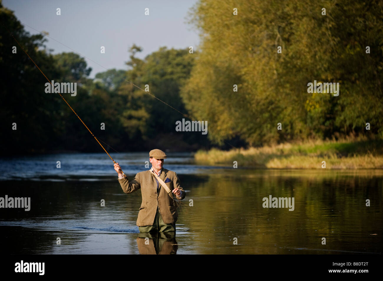 Wales; Wrexham. A trout fisherman casting to a fish on the River Dee ...