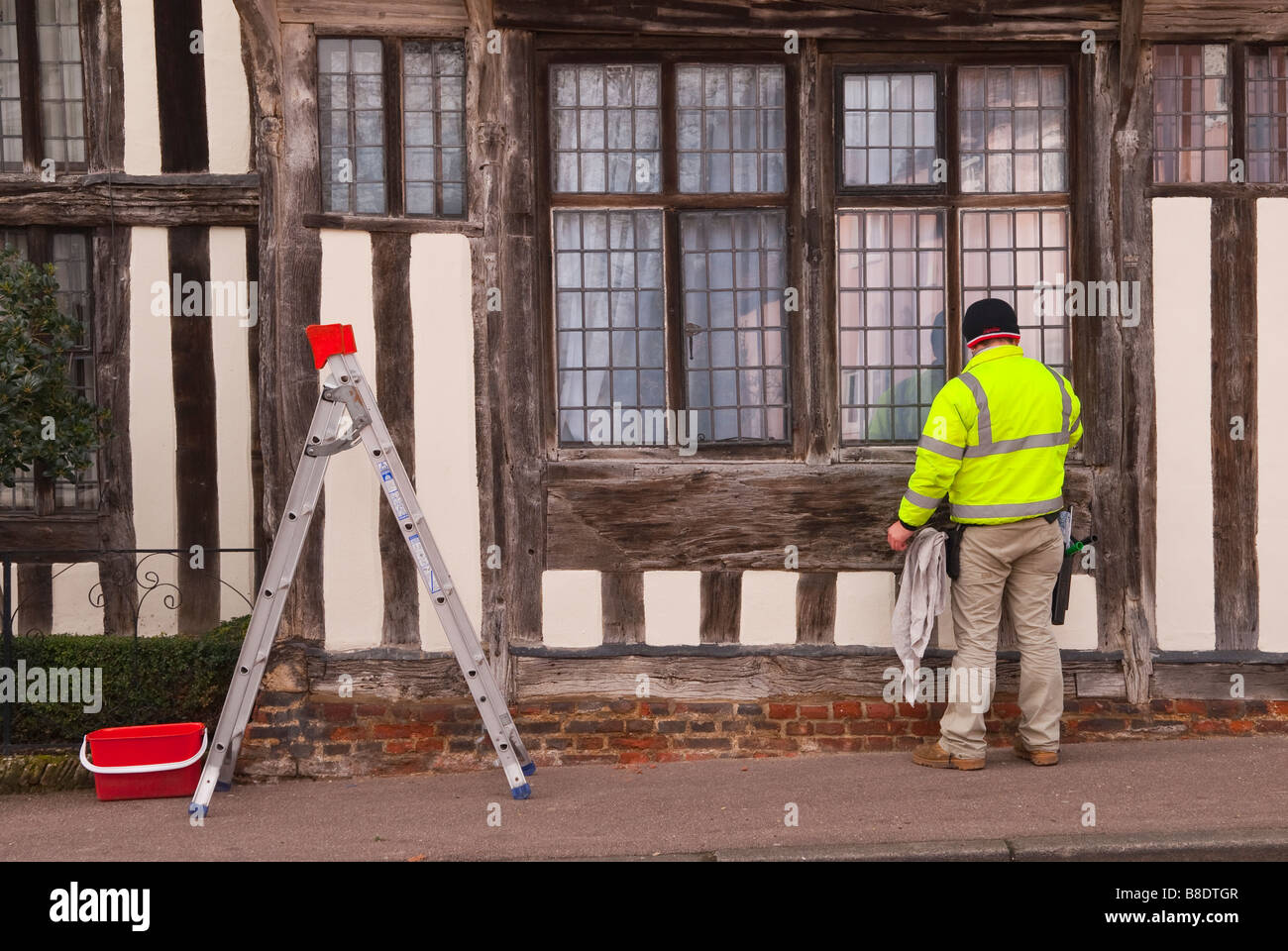 A window cleaner cleaning the leaded windows of a tudor house hotel in ...