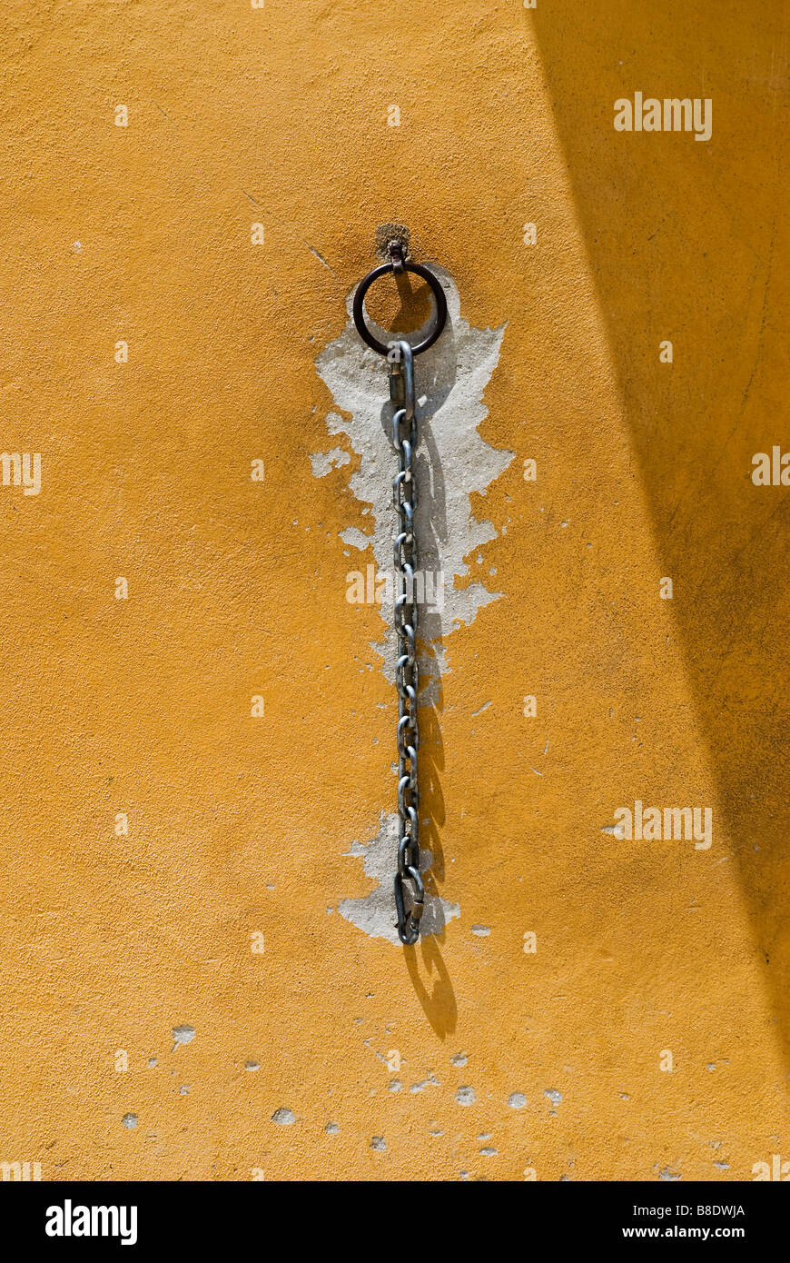 A metal chain on a yellow cocrete wall Stock Photo - Alamy