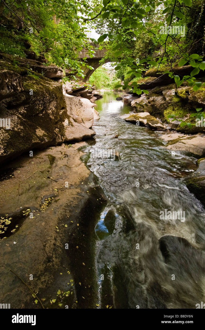 A river flows over rocks in Yorkshire, England. A bridge stands in the ...