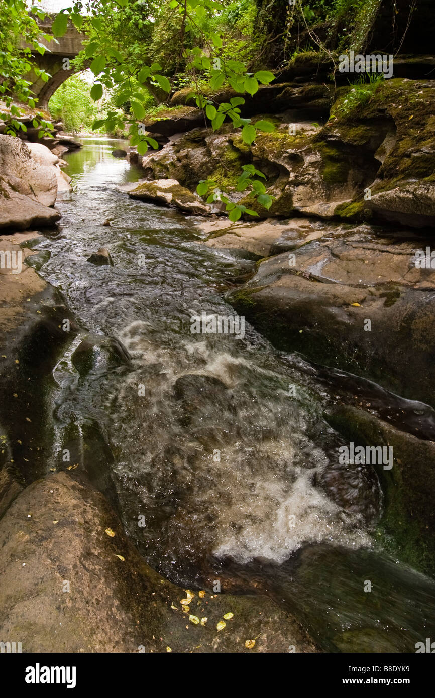 A river flows over rocks in Yorkshire, England. A bridge stands in the ...