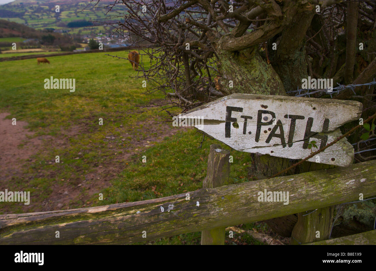 Homemade footpath direction sign fixed to stile on hillside track above ...