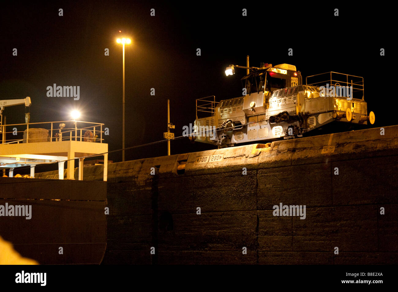 Panama Canal mule helps centering a ship during a night transit. Panama ...