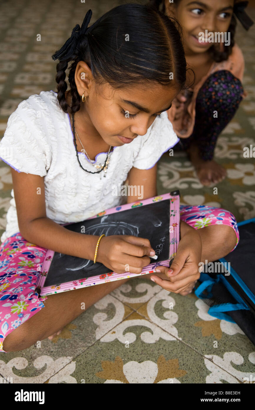 Schoolgirl working on a small blackboard, doing her homework. Hazira ...