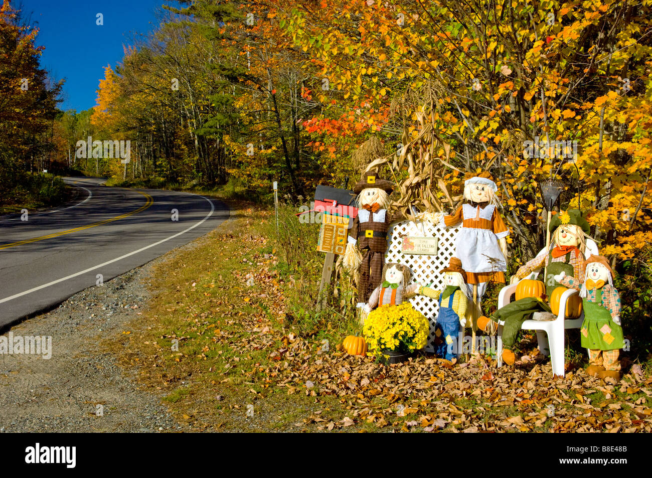 An autumn display of a group of yard scarecrows with pumpkins and ...