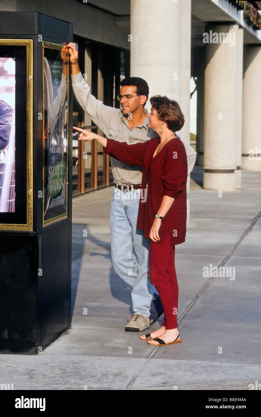 Couple discuss movie poster outside theatre Stock Photo - Alamy