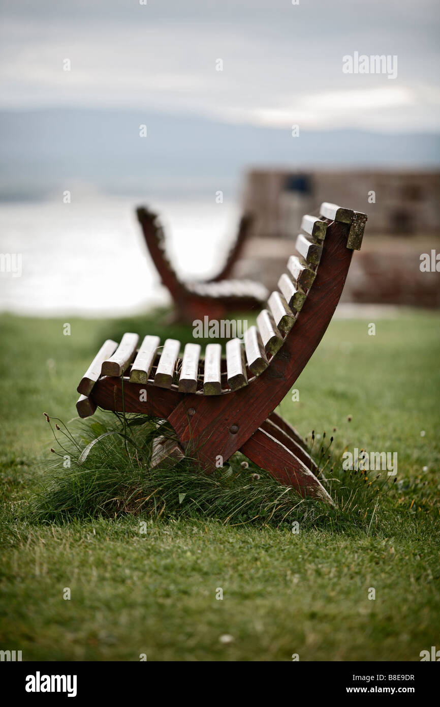 Profile view of three benches, in the distance is a harbour wall Stock ...