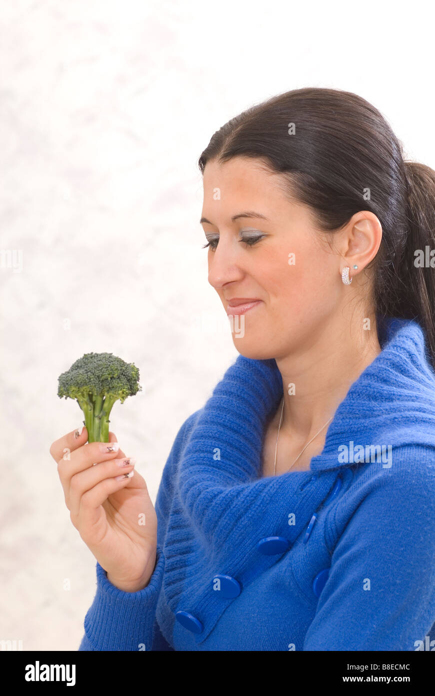 Profile view of a young woman eating green raw broccoli Stock Photo - Alamy