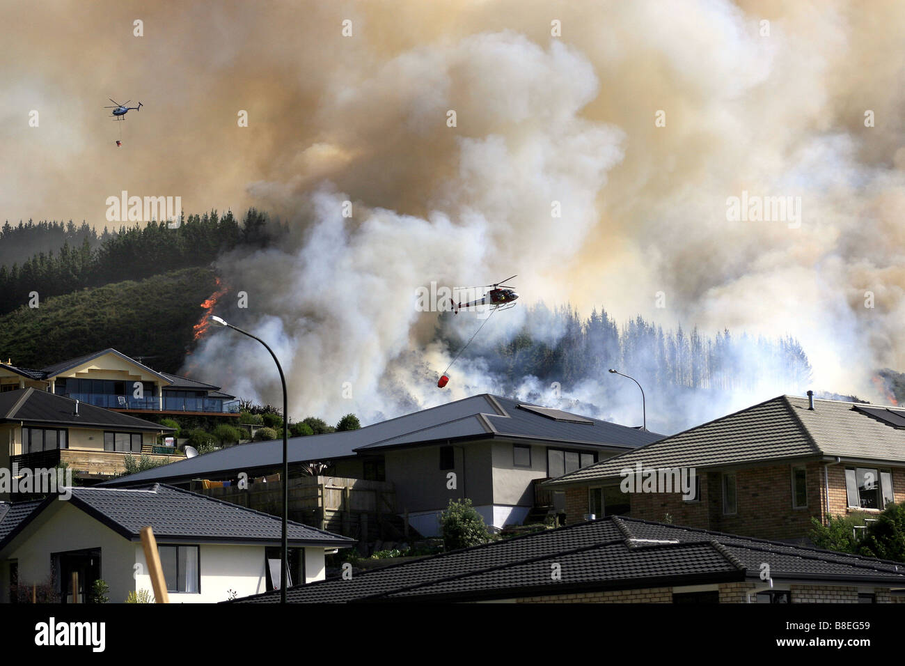 helicopters with monsoon buckets fighting a bush fire raging in forest ...