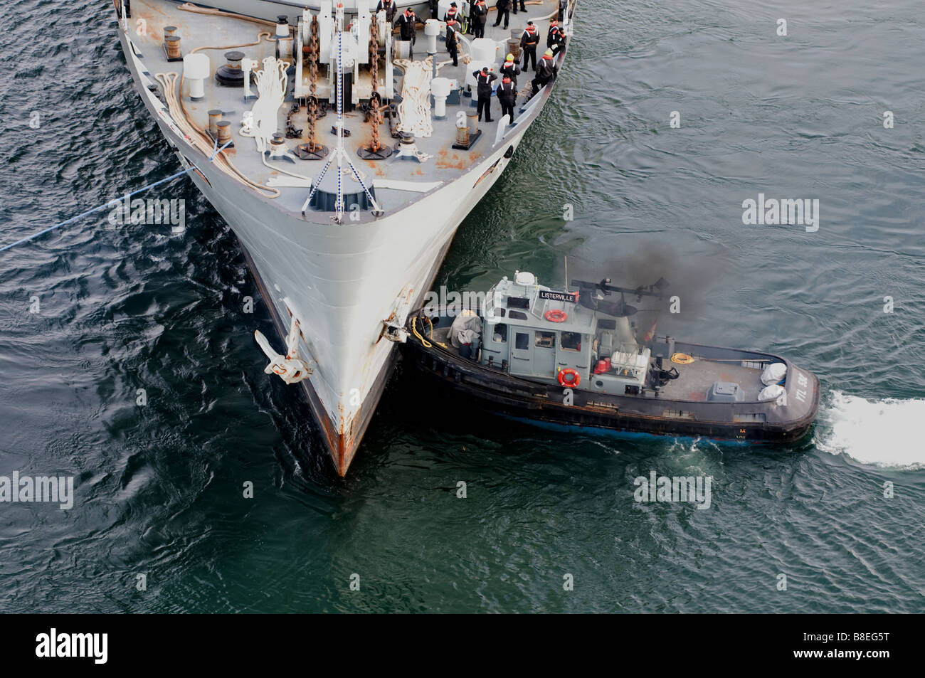 Navy ship being pushed by a tug boat Stock Photo - Alamy