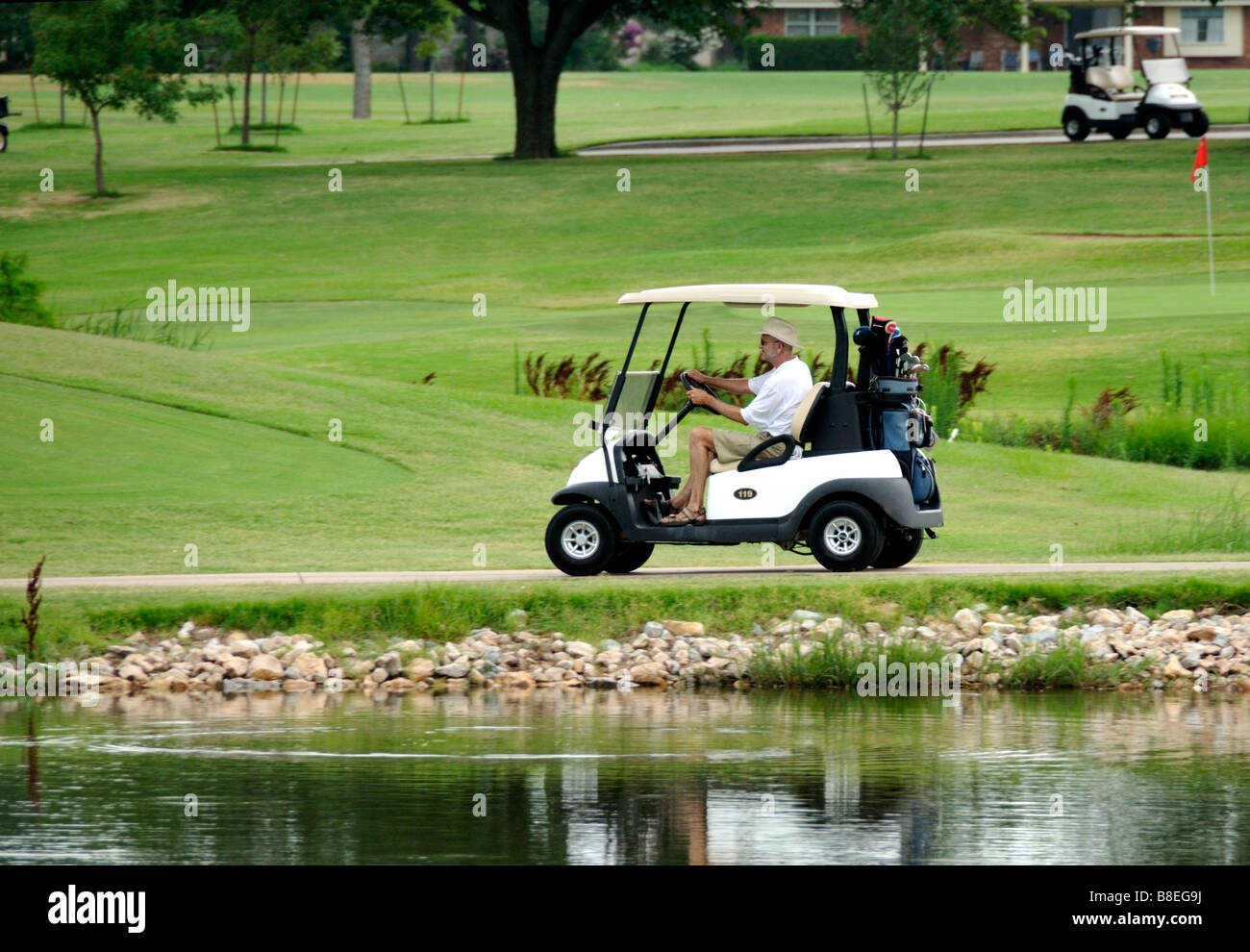 A senior man drives a golf cart past a water hazard on Hefner golf ...