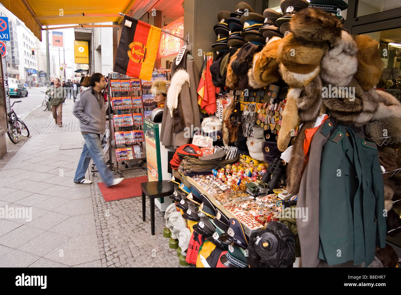Tourists passing close by to the stand selling souvenirs of DDR ...