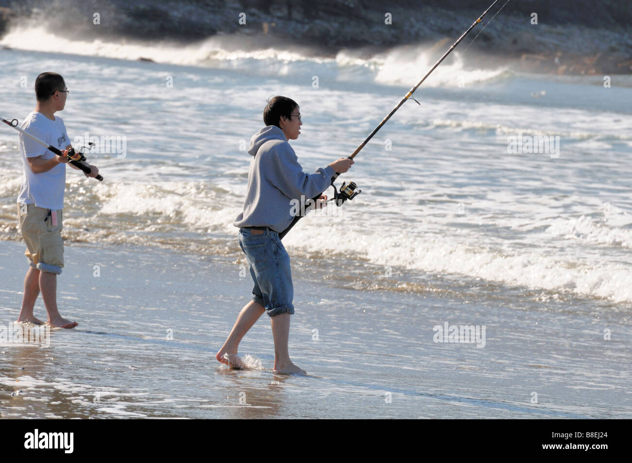 Two young men fishing at the shore Stock Photo - Alamy