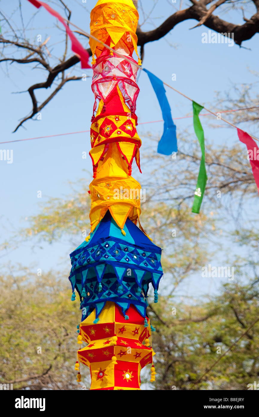 Colorful cylindrical banners hanging from tree at the Surajkund Mela ...