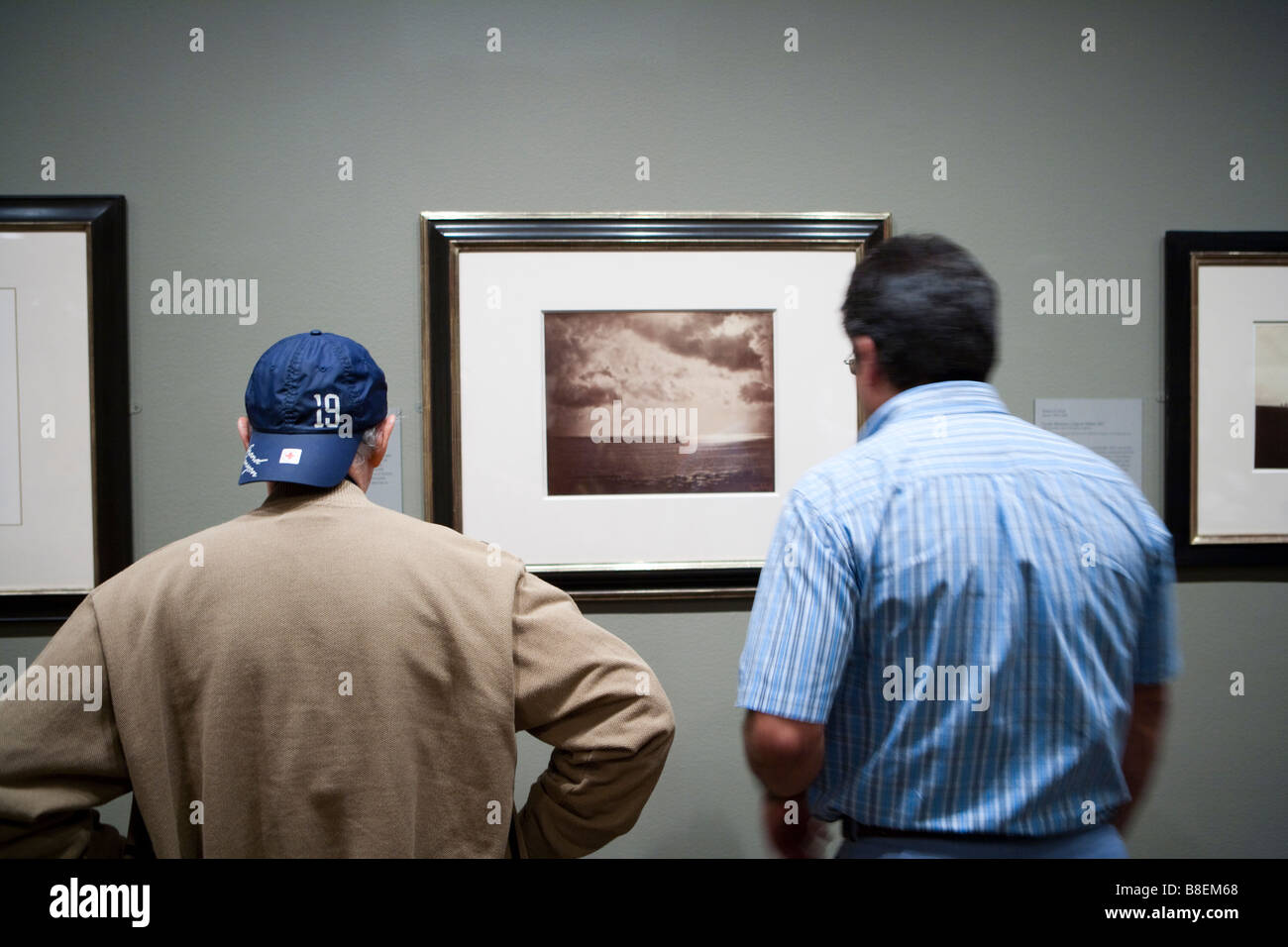 Two men looking at framed pictures exhibited in a gallery Stock Photo ...
