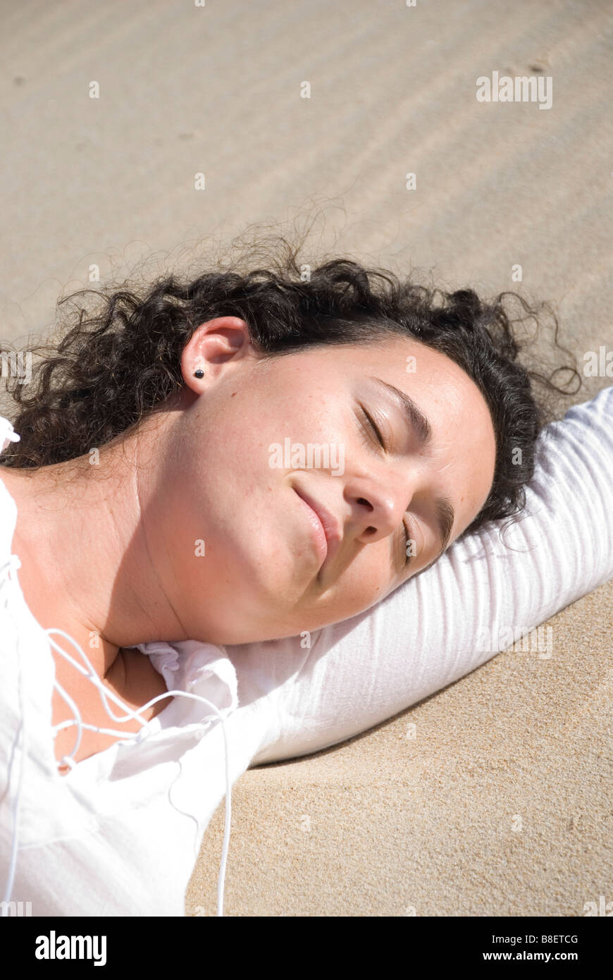 Young woman lying in the sand Stock Photo - Alamy